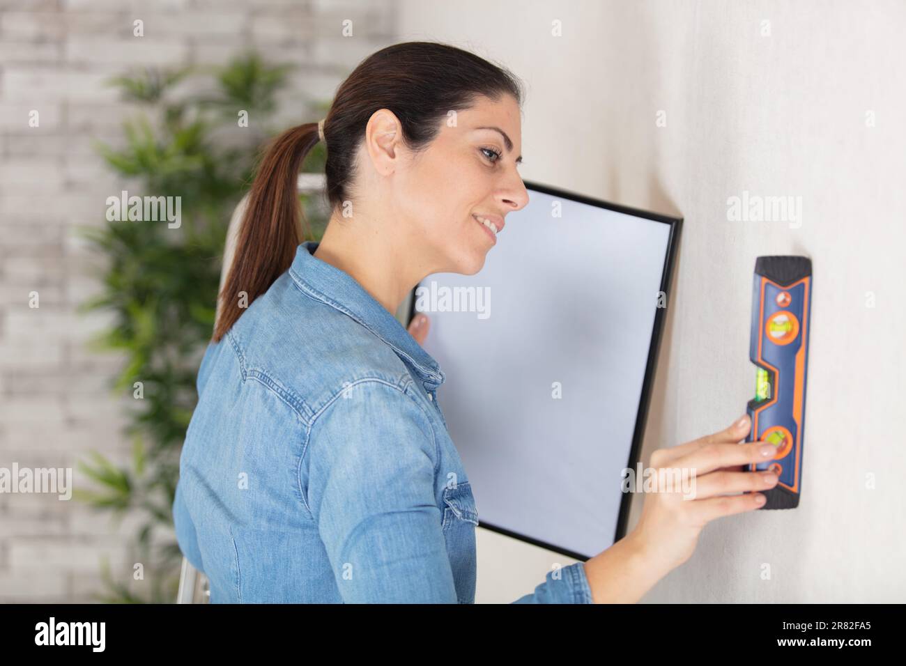 woman testing wall with spirit level to hang a picture Stock Photo - Alamy