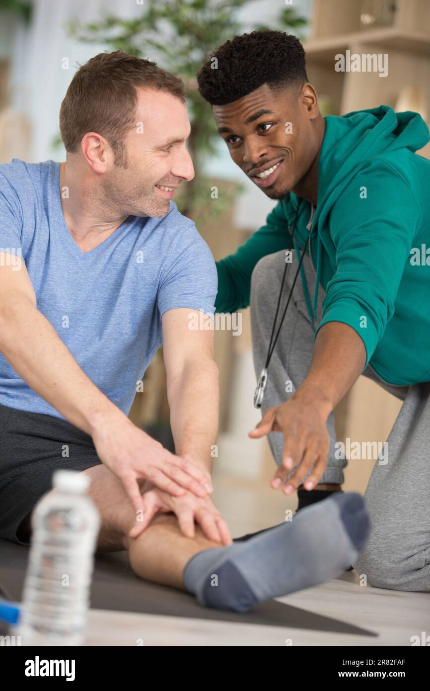 trainer shows man how to do the leg exercise Stock Photo - Alamy