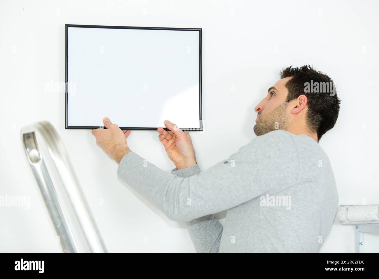 man adjusting the angle of wall frame Stock Photo - Alamy