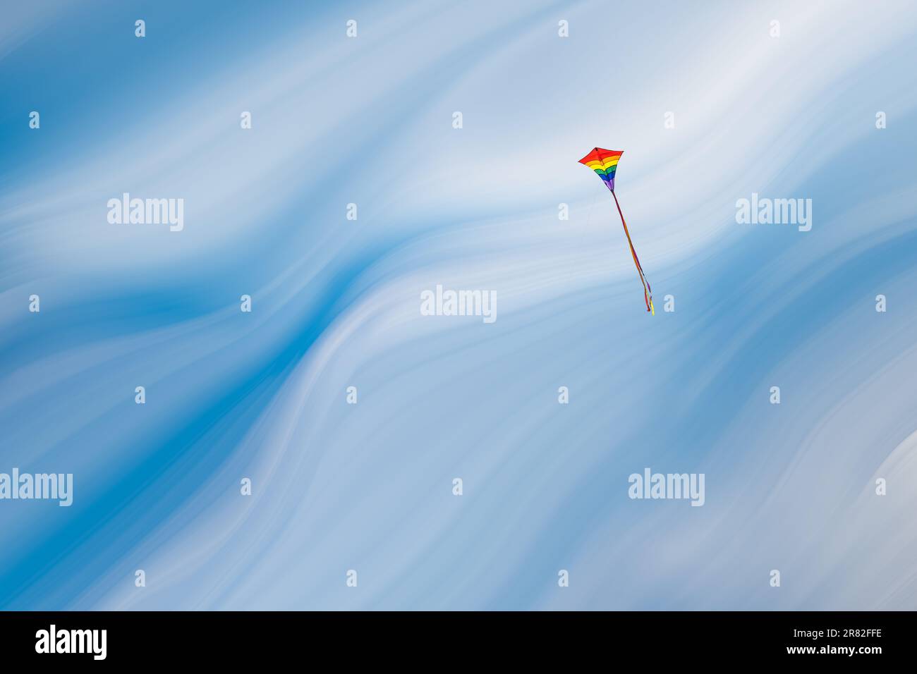 Rainbow kite against a blue cloudy sky, and the sky is streaked after ...