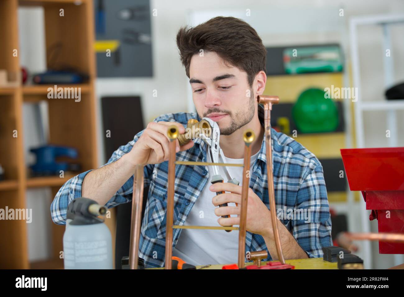 young male plumber tightening pipe fitting with wrench Stock Photo - Alamy