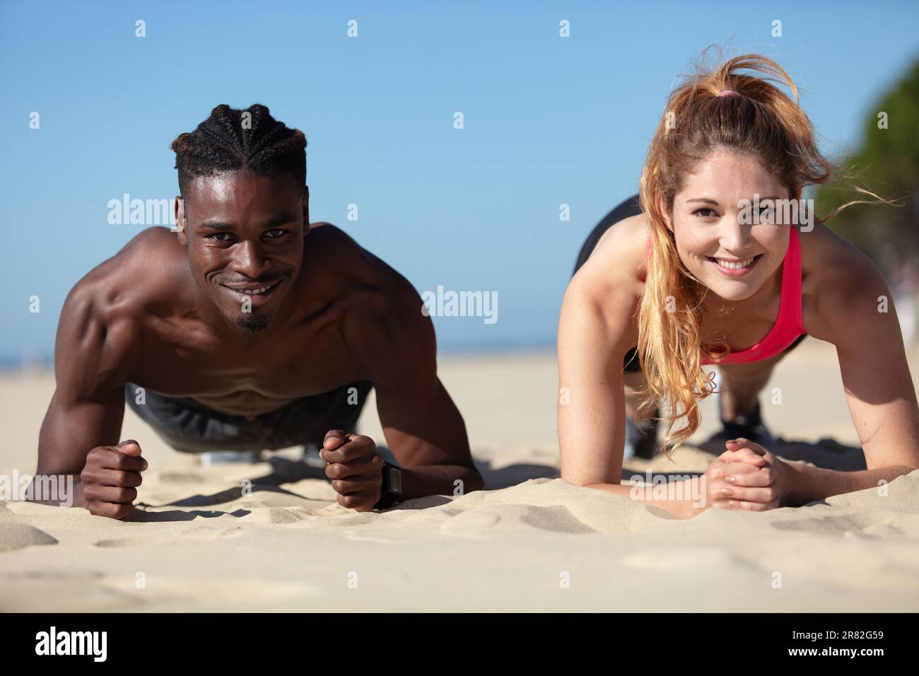 young fit woman and her partner smiling while practicing plank Stock ...