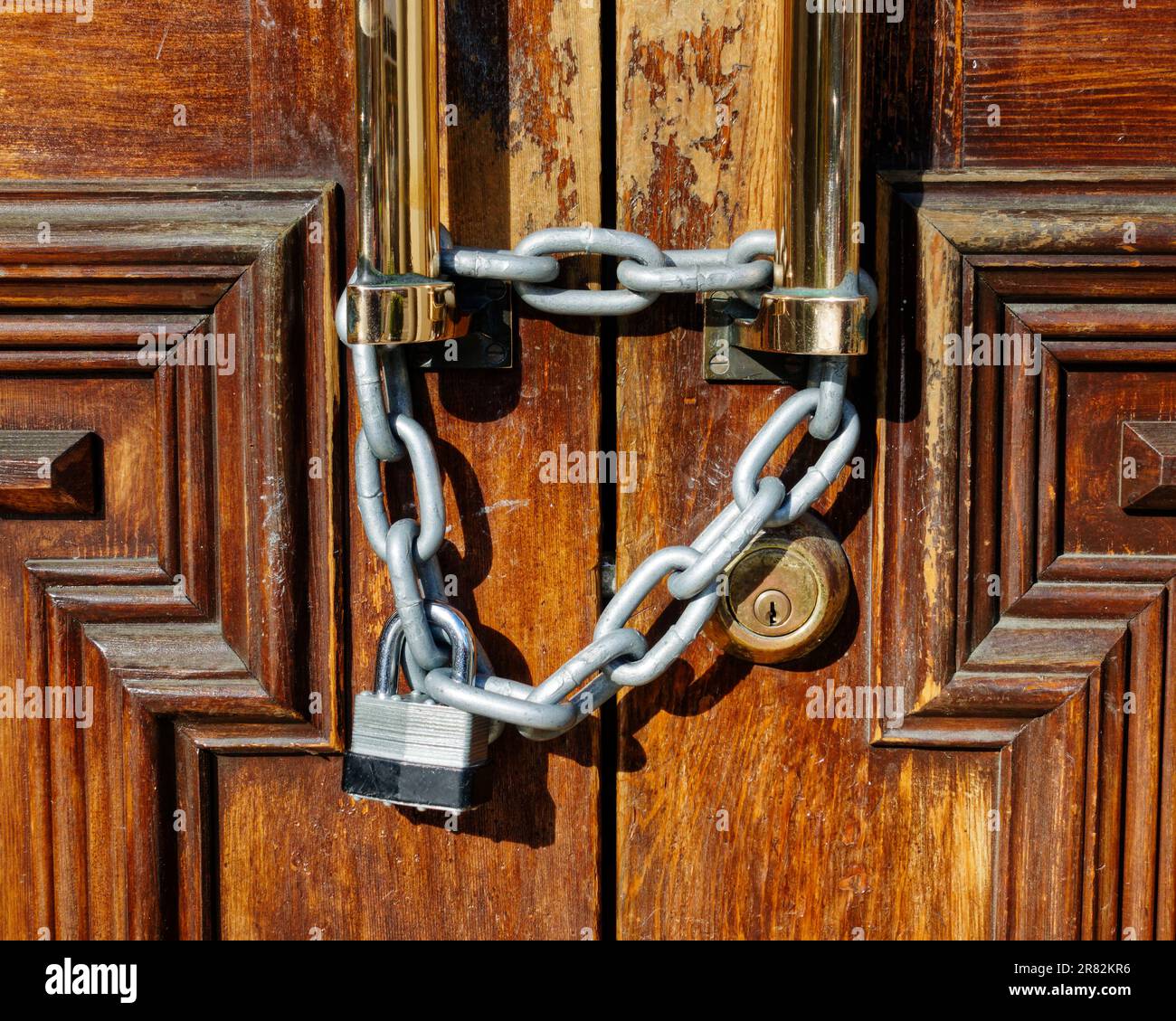 A large chain and lock preventing entry through ornate wooden doors ...