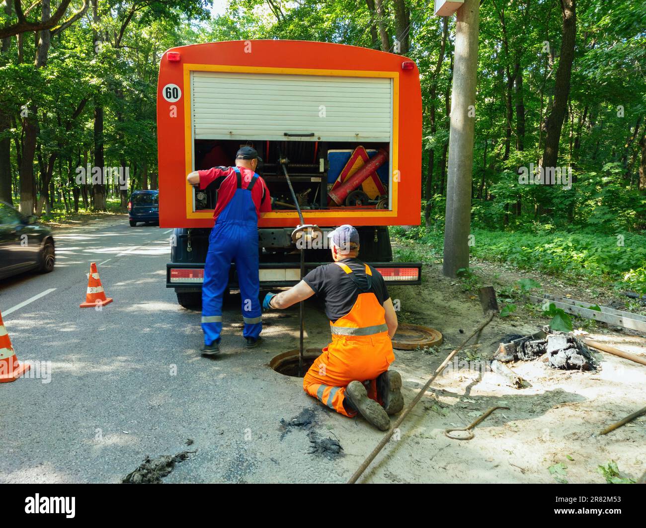 Sewer workers cleaning manhole and unblocking sewers the street ...