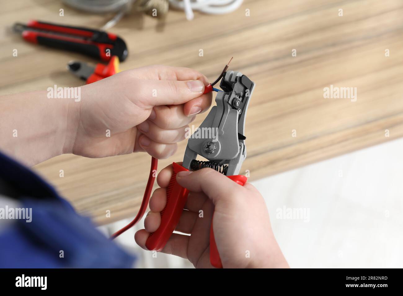 Professional electrician stripping wiring at wooden table, above view ...