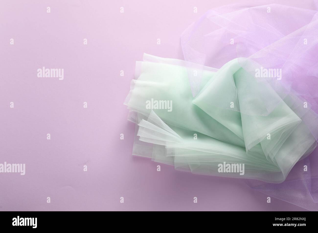Beautiful tulle fabric on lilac background, flat lay. Space for text ...