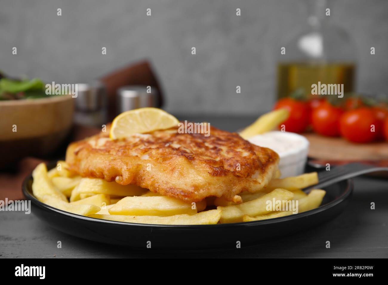 Tasty soda water battered fish, lemon slice and potato chips on dark ...