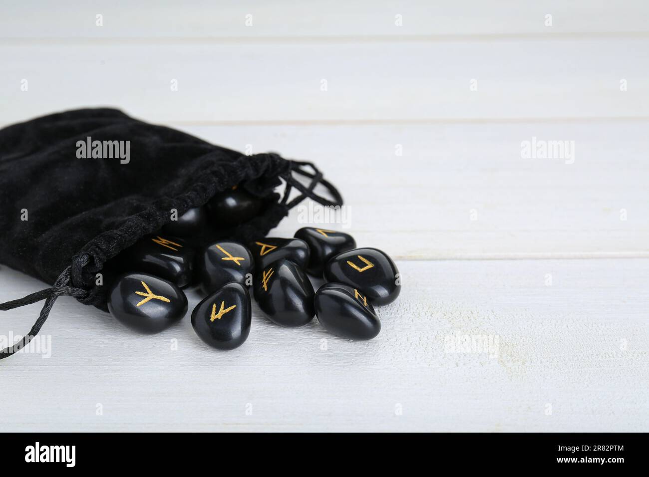 Bag with black rune stones on white wooden table Stock Photo - Alamy