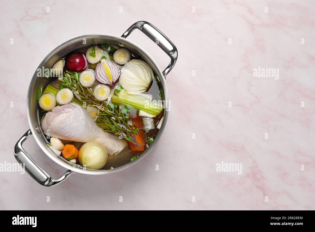 Different ingredients for cooking tasty bouillon in pot on pink marble ...