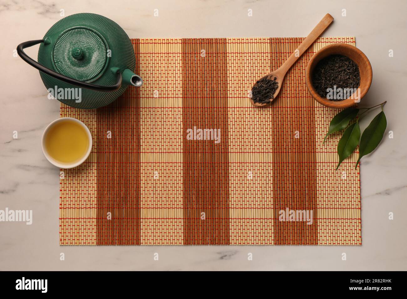 Flat lay composition with bamboo mat, dry tea leaves and teapot on ...