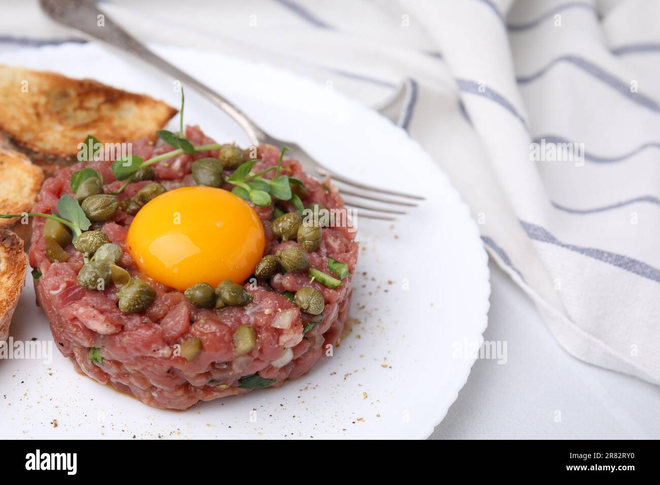 Tasty beef steak tartare served with yolk, capers and toasted bread on ...