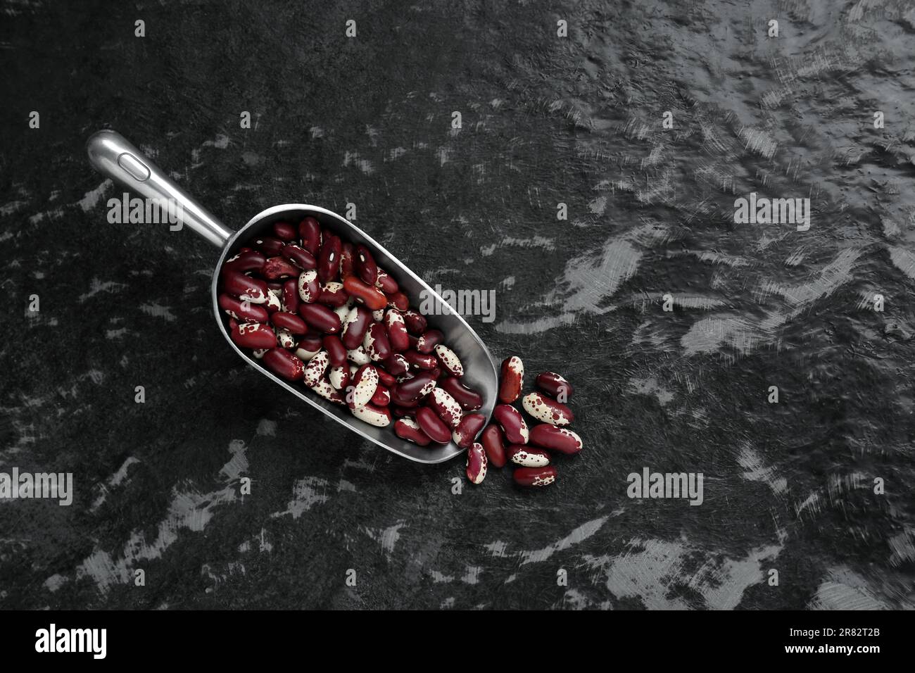 Metal scoop with dry kidney beans on black textured table, flat lay ...