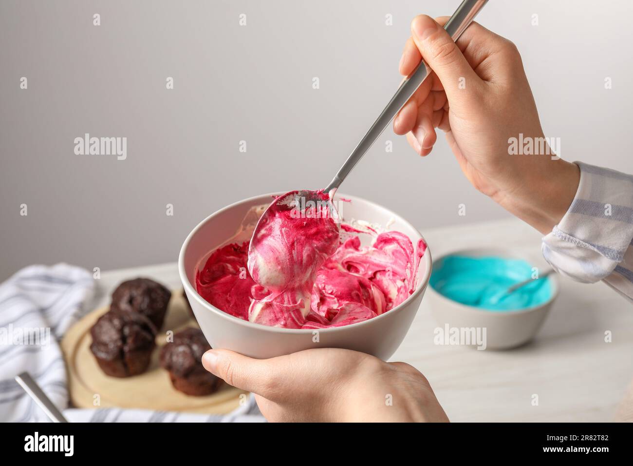 Woman mixing pink food coloring indoors, closeup. Decorate cupcakes ...