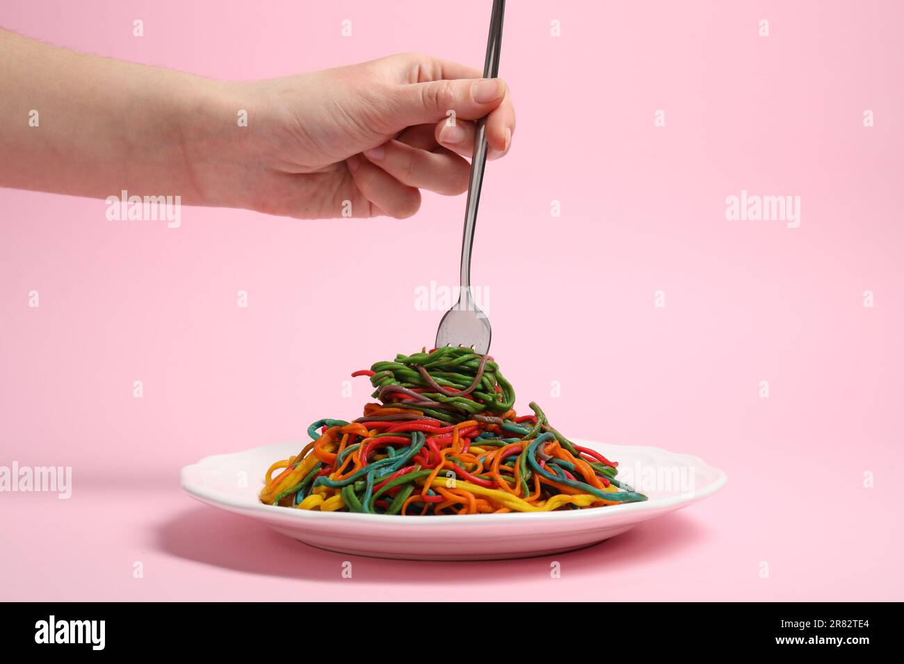 Woman eating delicious spaghetti painted with different food colorings ...