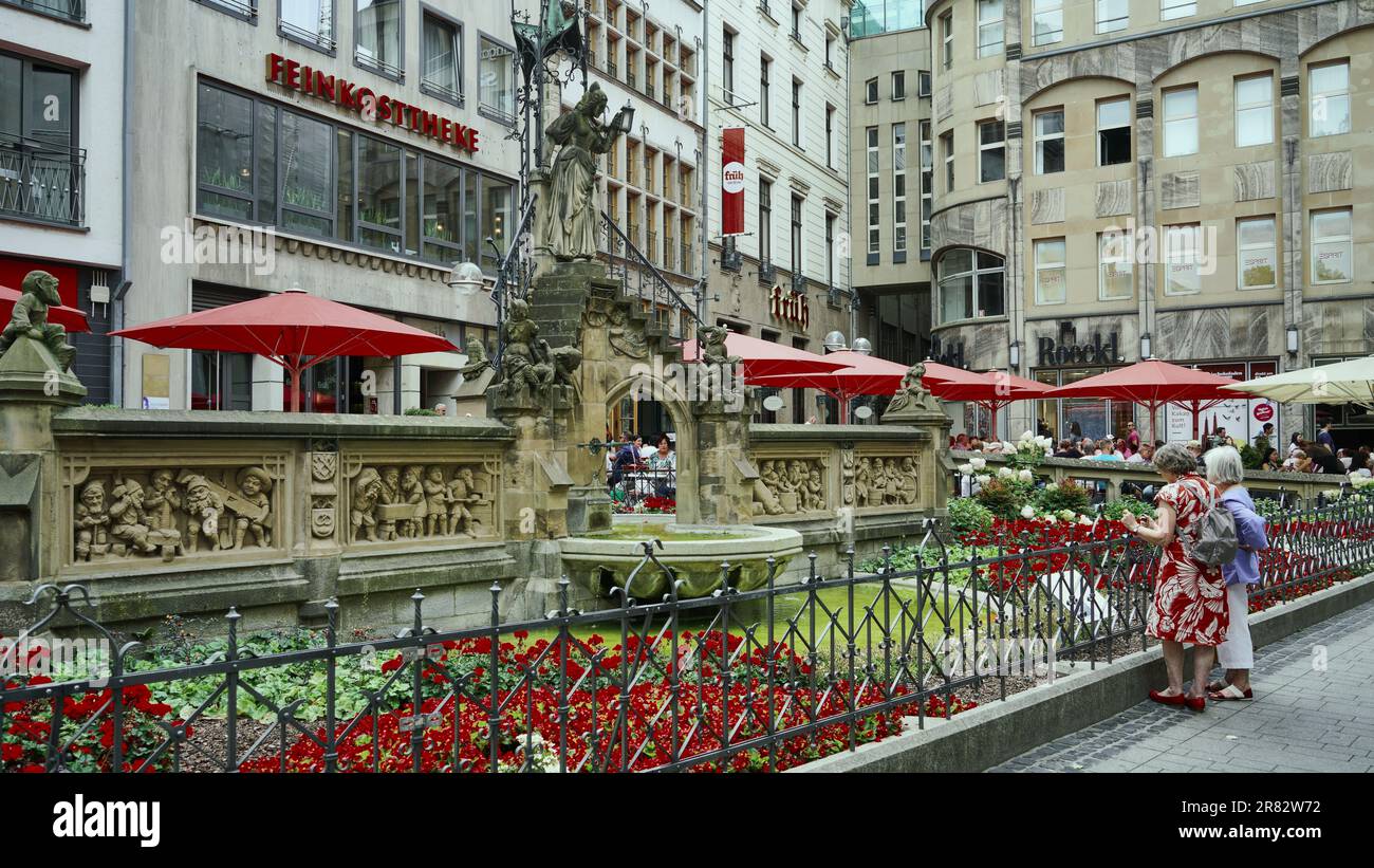 2 senior women enjoy the red flowers and water fountain in a garden ...