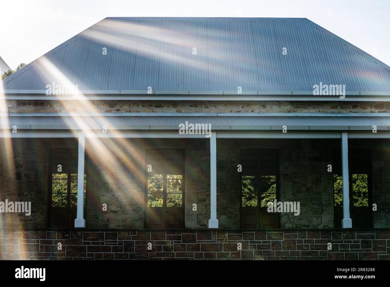 Afternoon sun rays streak across an old stone building in Darwin ...