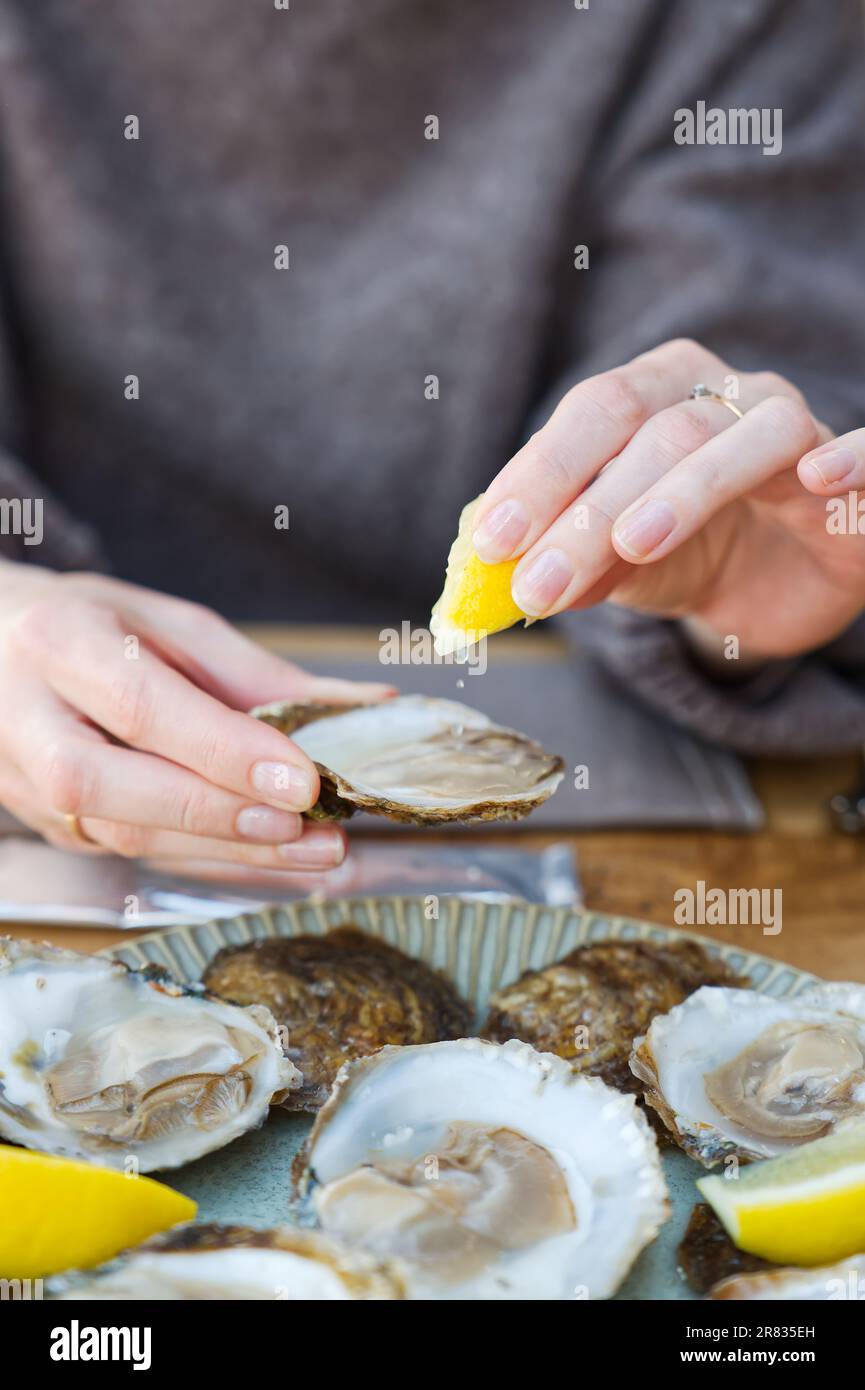 Beautiful Woman eating fresh oysters and drinking in restaurant ...