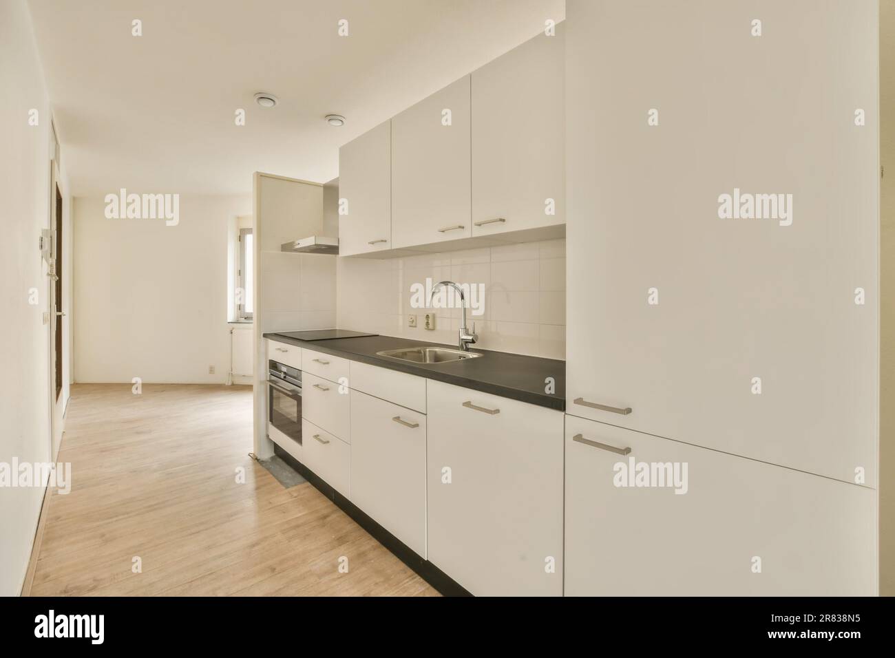 an empty kitchen with white cabinets and black counter tops on the ...