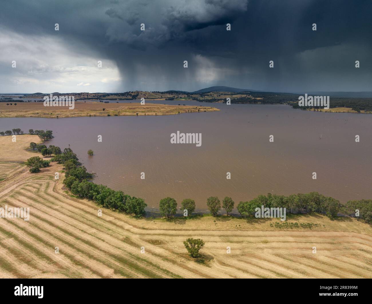 Aerial view of heavy rain falling from dark clouds over a reservoir ...