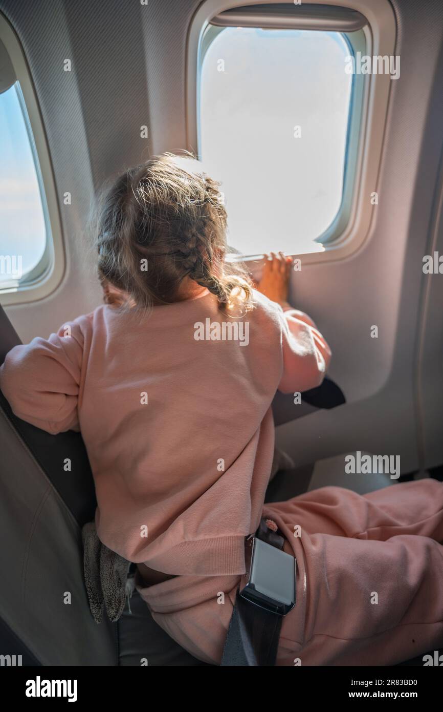 Cute little girl traveling by an airplane. Child sitting by aircraft ...