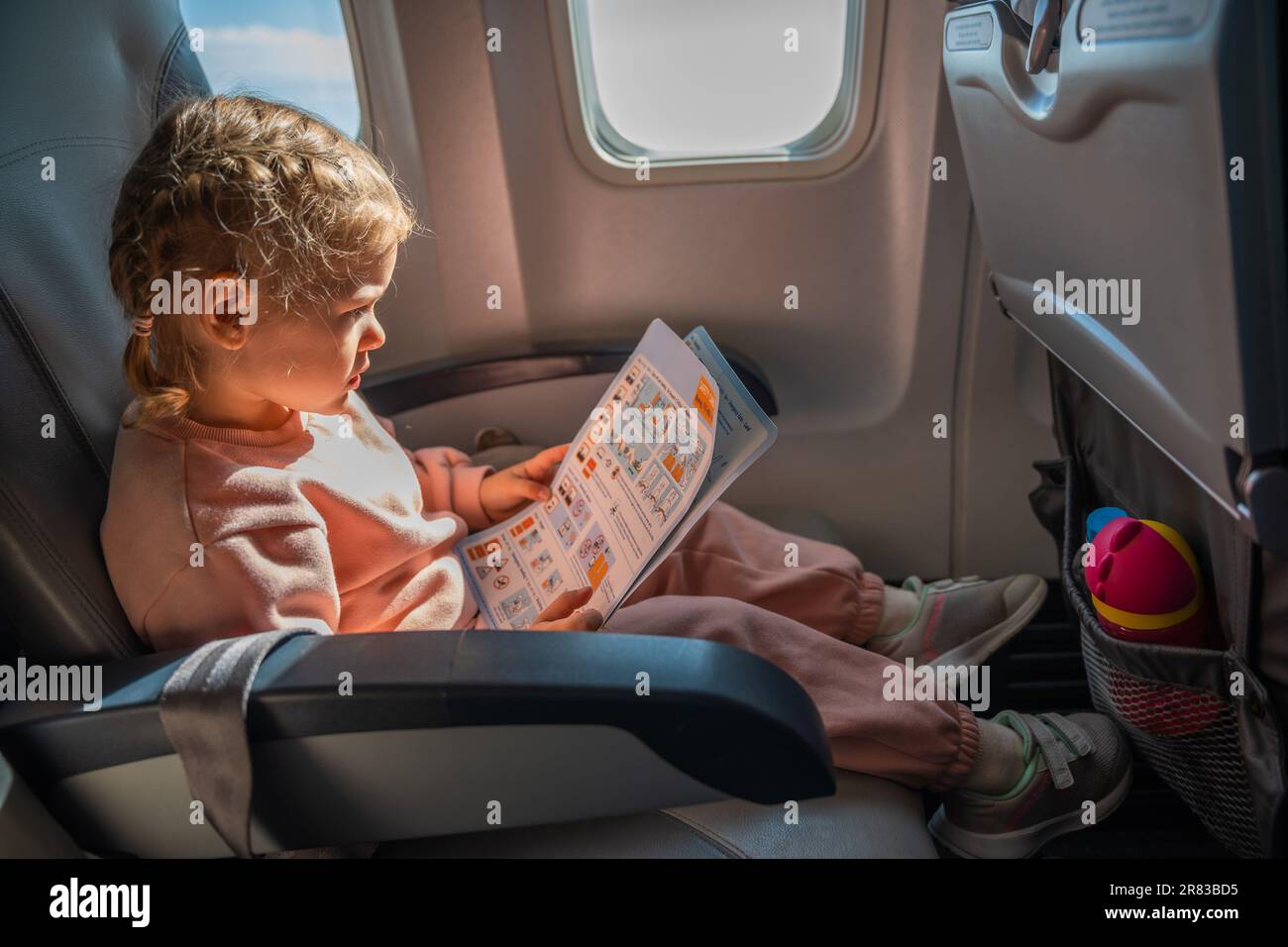 Cute little girl traveling by an airplane. Child sitting by aircraft ...
