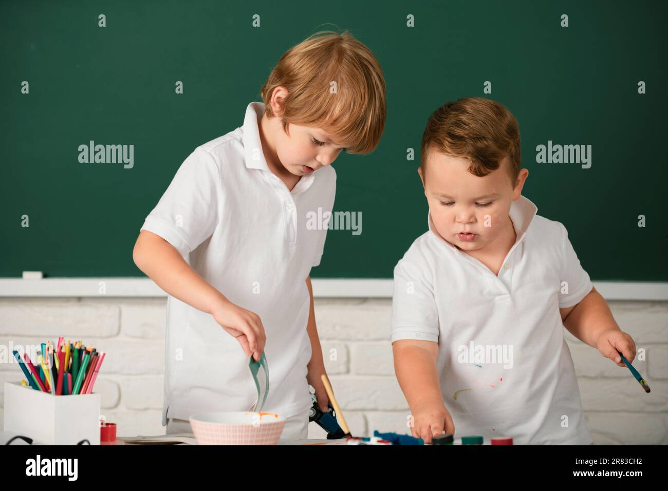 Children boys pupils drawing with coloring pens, painting with early ...
