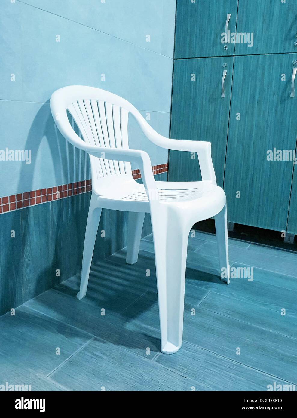 One white plastic chair stands near the wooden cabinets in the locker ...