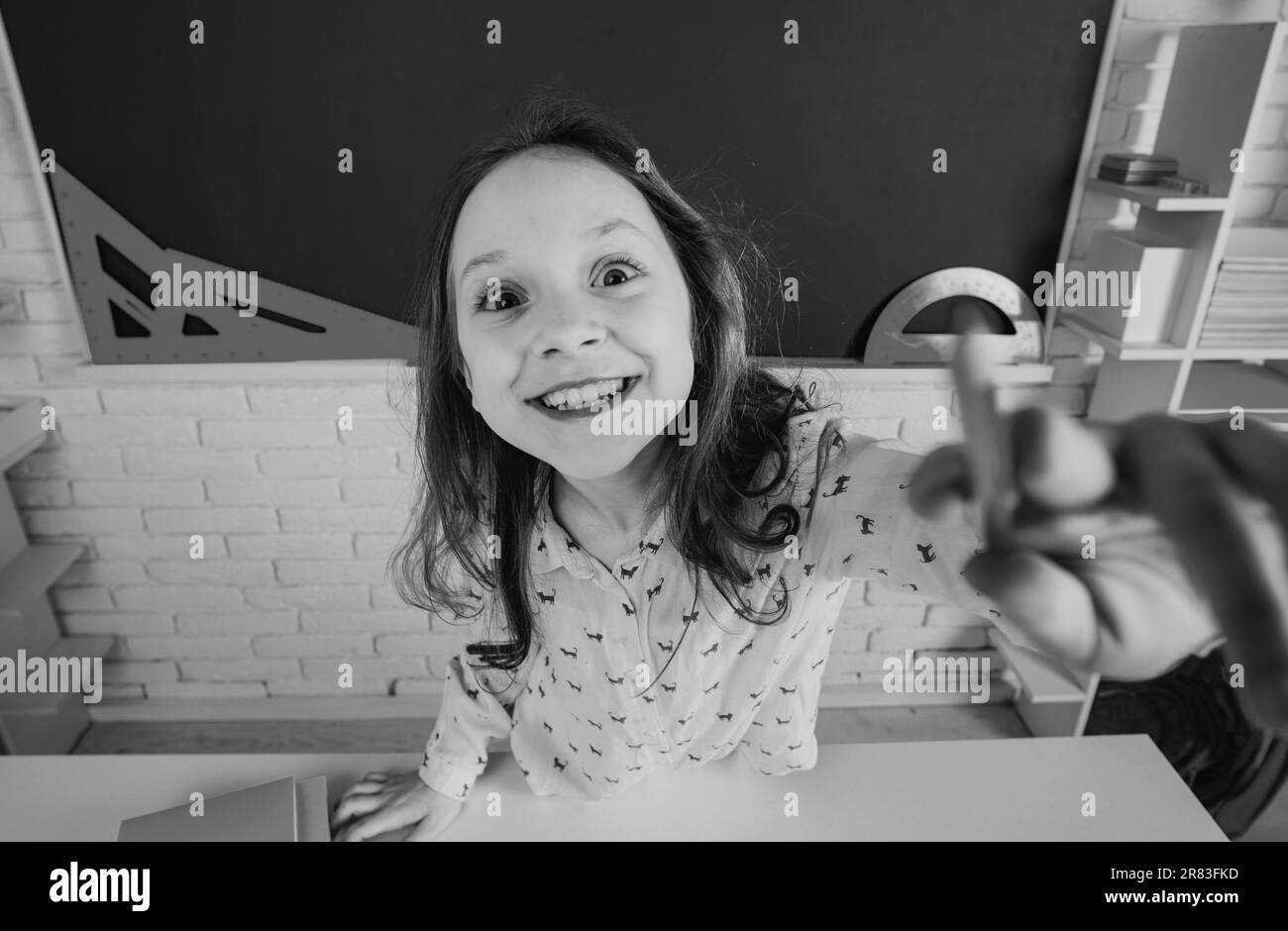 Funny child girl in classroom near blackboard desk. Kid is learning in ...