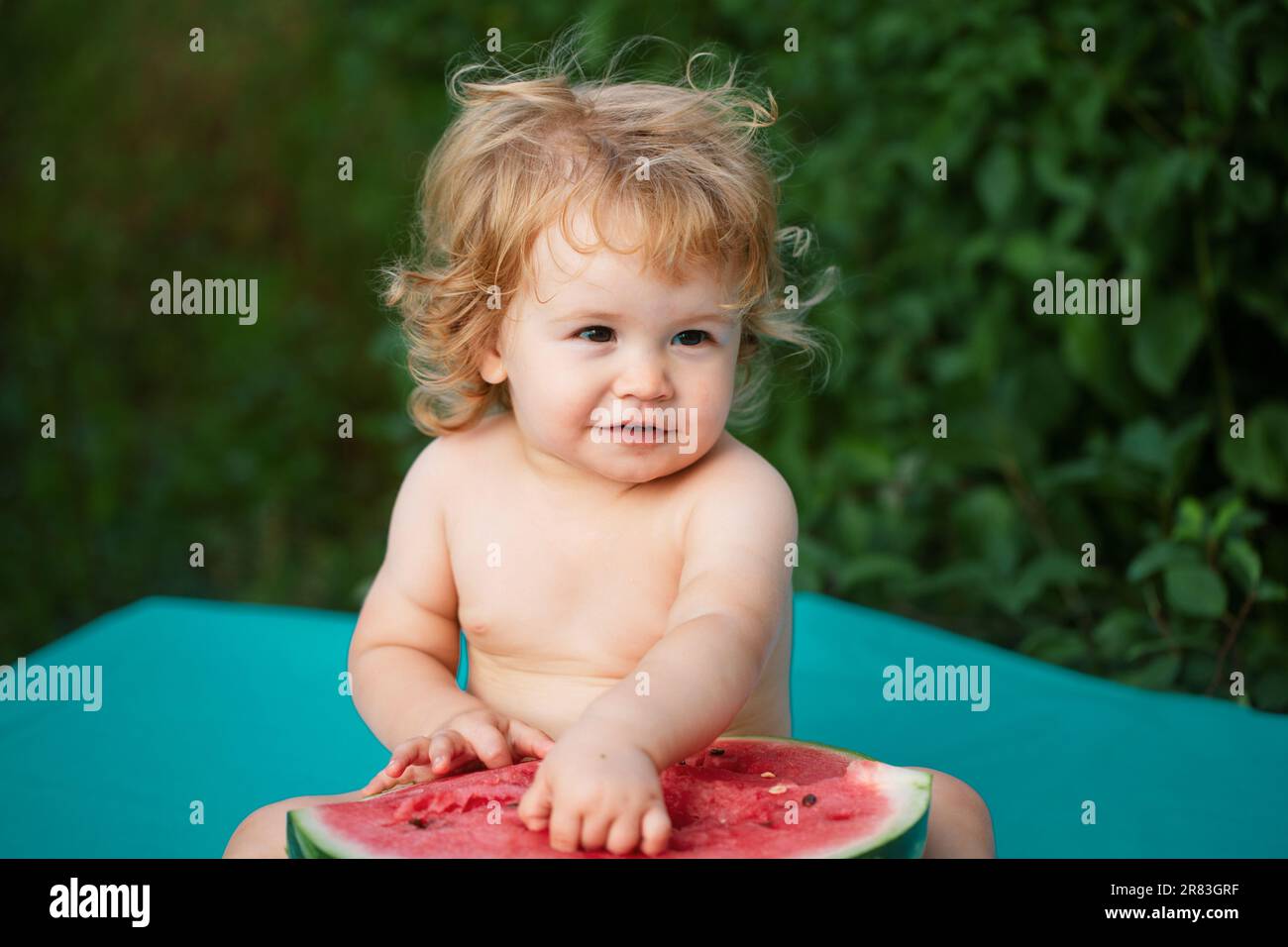 Little baby eating watermelon red in the garden sitting on the grass ...