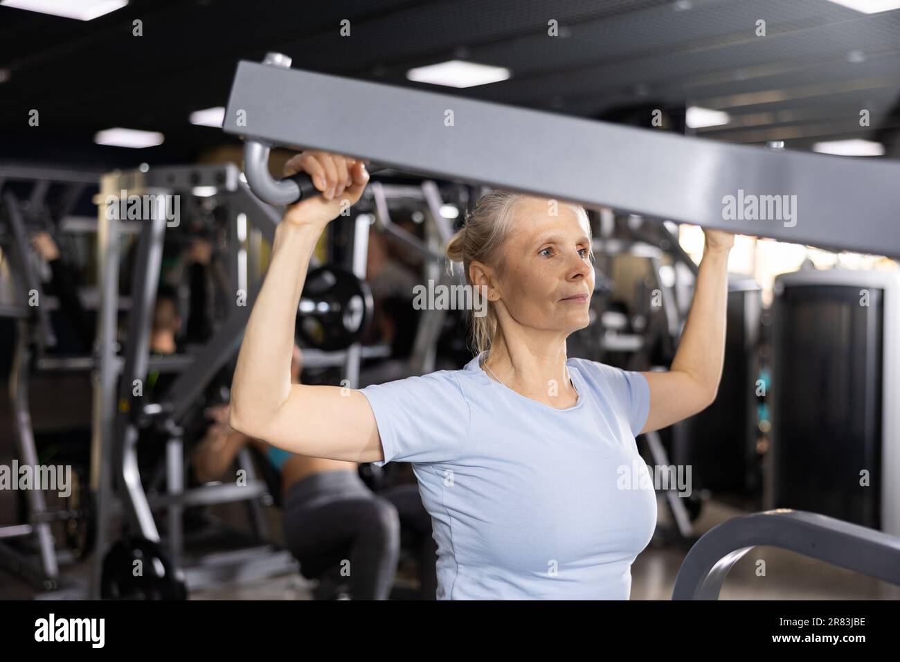 Elderly woman exercising on lat pull down lever machine Stock Photo - Alamy