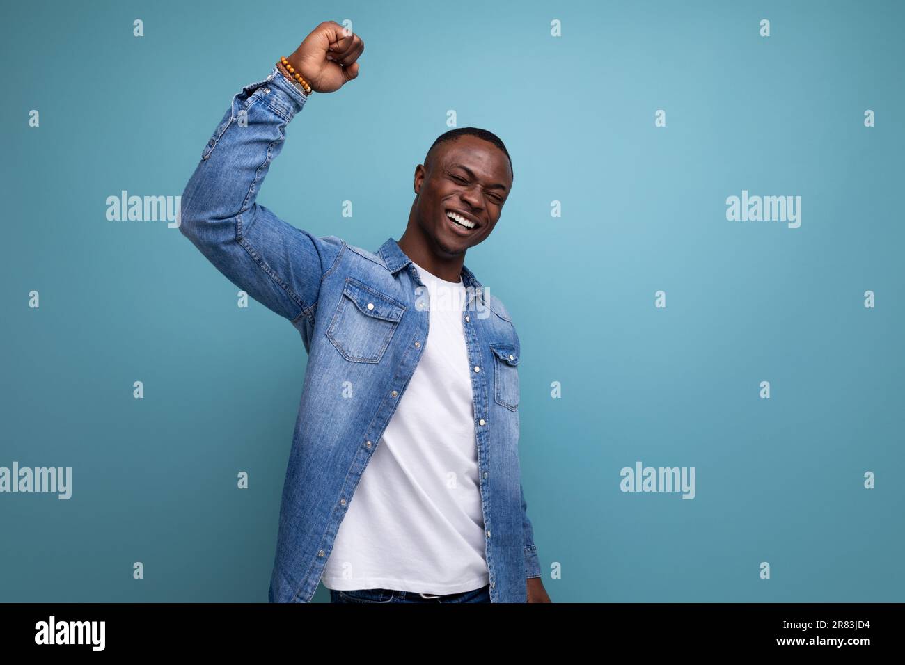 kind friendly young american man in denim clothes on blue background ...