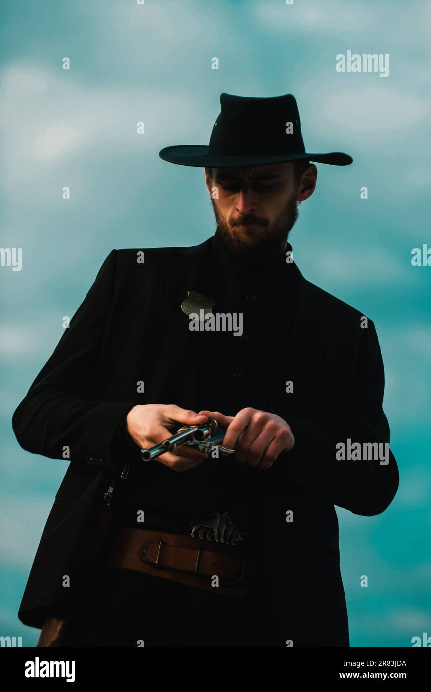 Cowboy shooter in black suit and cowboy hat. Serious man with wild west ...