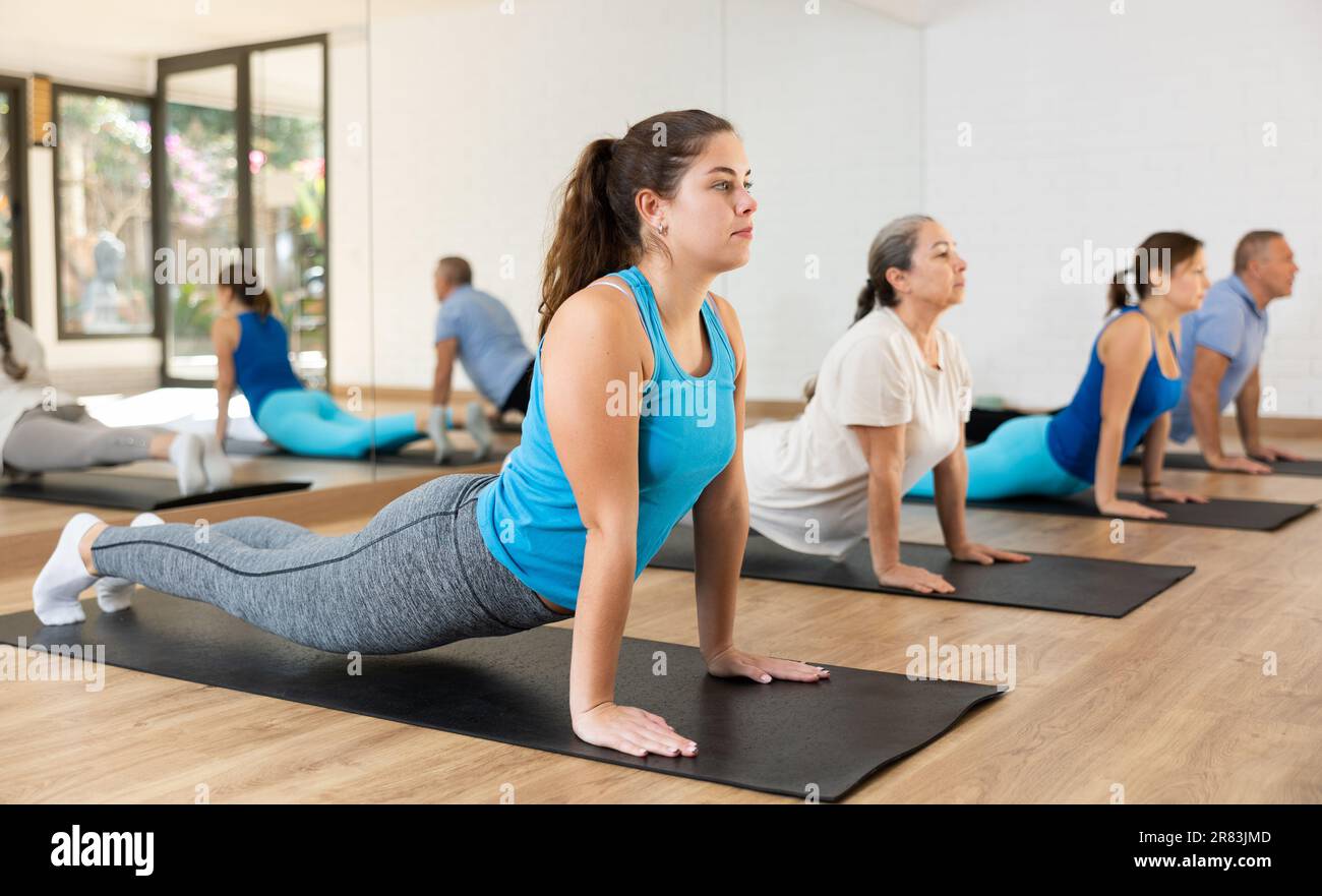 Class of male and women of different ages in active wear doing cobra ...