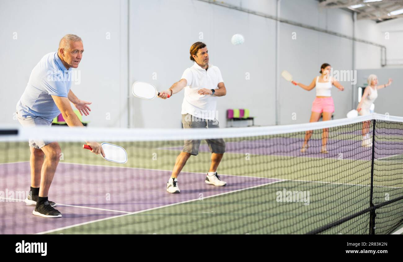 Aged man playing doubles pickleball match with male partner Stock Photo ...
