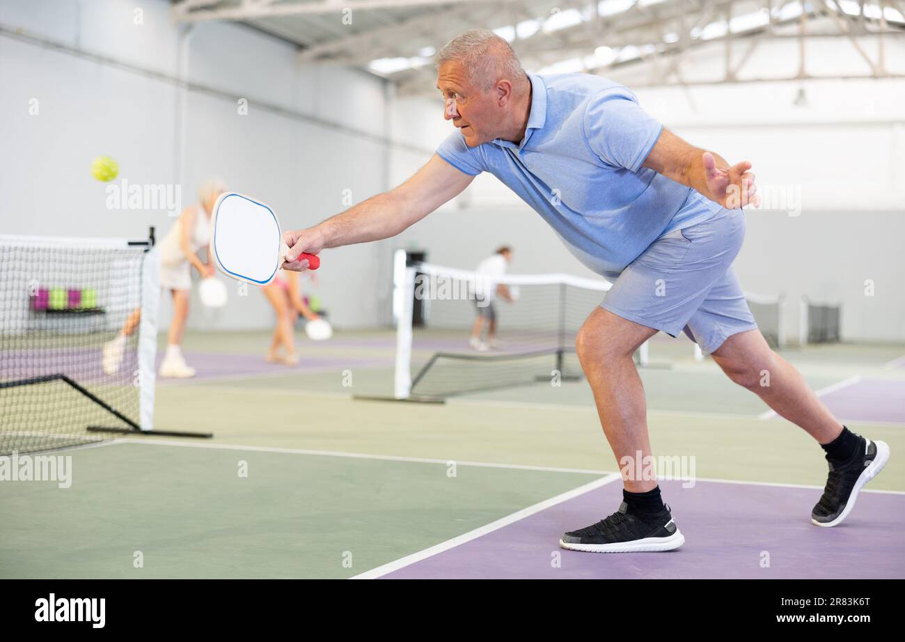 Emotional elderly man playing pickleball on indoor court Stock Photo ...