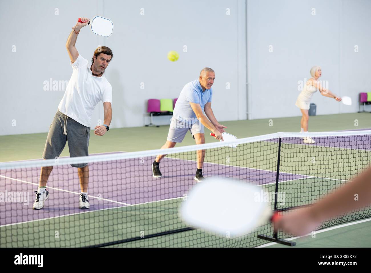 Adult man playing doubles pickleball with aged partner indoors Stock ...