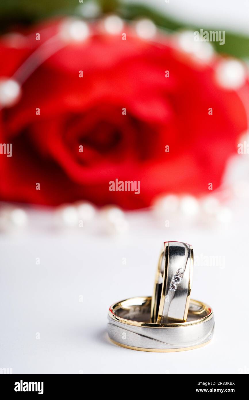 Two rings in front of a red rose and a pearl necklace Stock Photo - Alamy