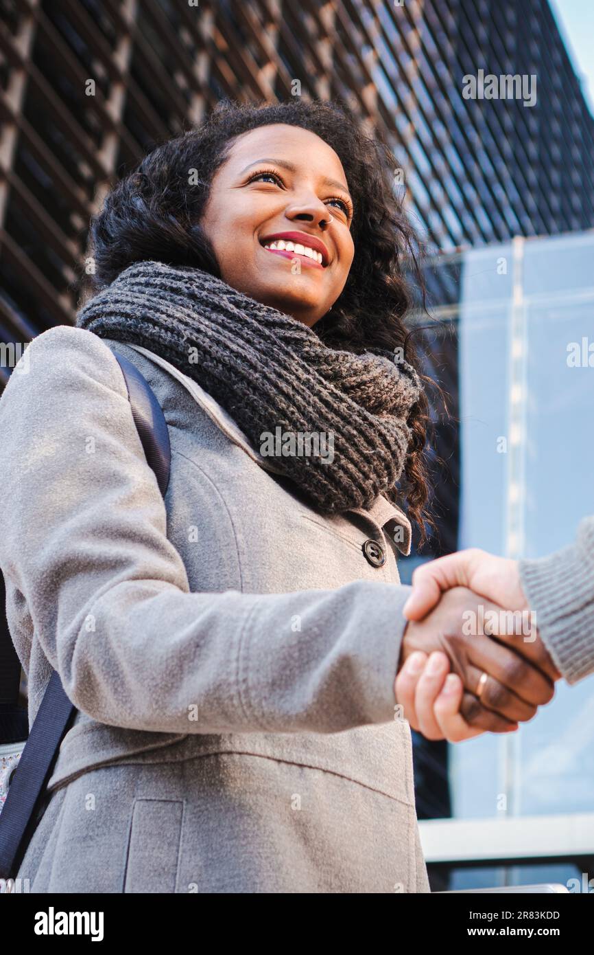 Vertical portrait of a young hispanic woman shaking hands with her ...