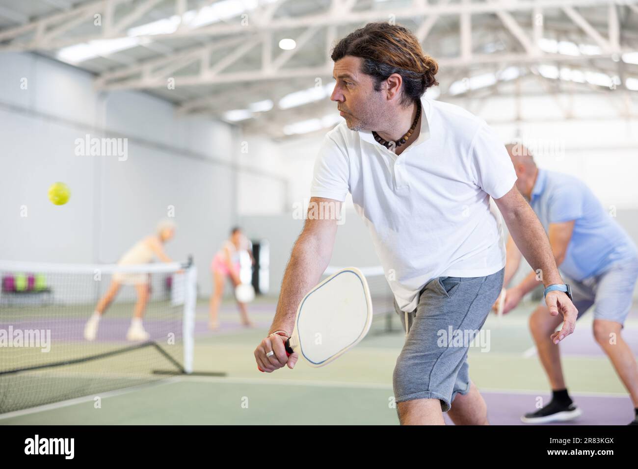Athletic men playing pickleball tennis on pickleball court indoors ...