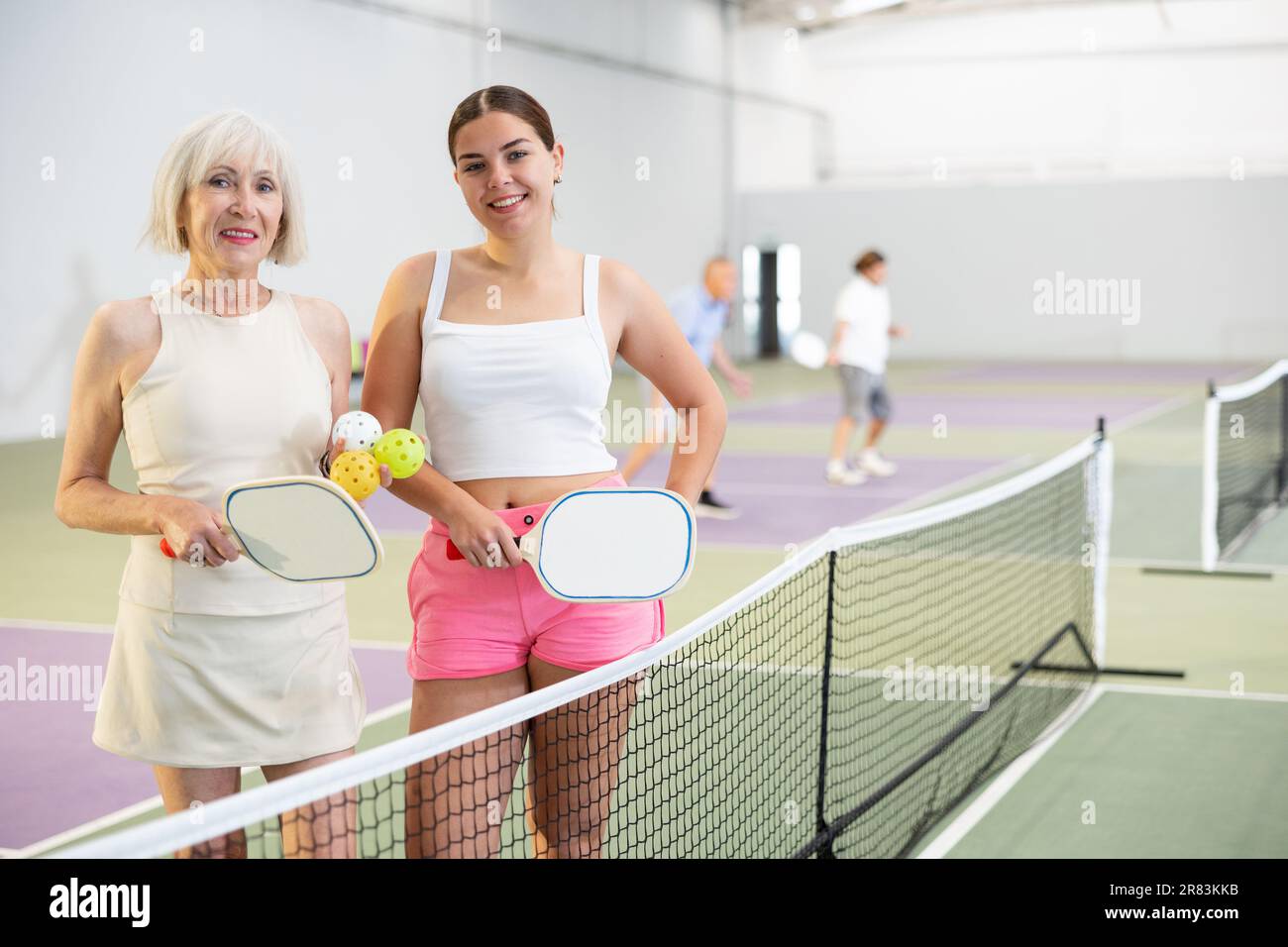 Two smiling female pickleball players standing on indoor court Stock ...