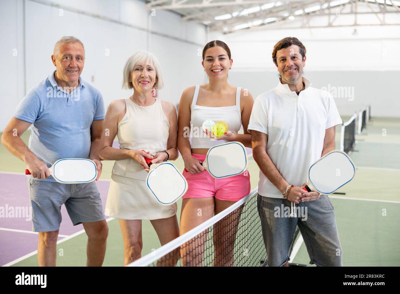 Smiling pickleball players with rackets and balls posing on court Stock ...