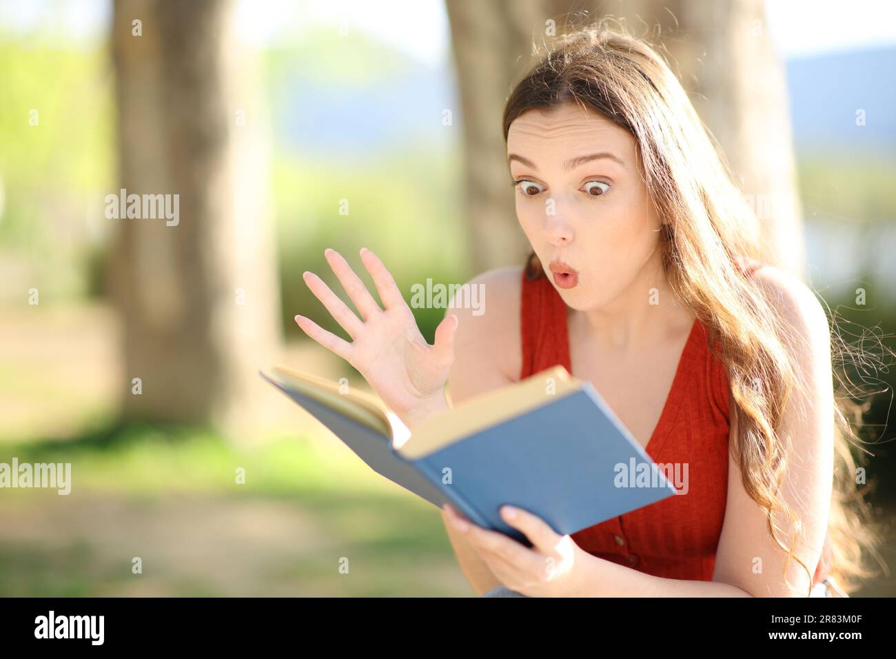 Surprised book reader reading amazing novel in nature Stock Photo - Alamy