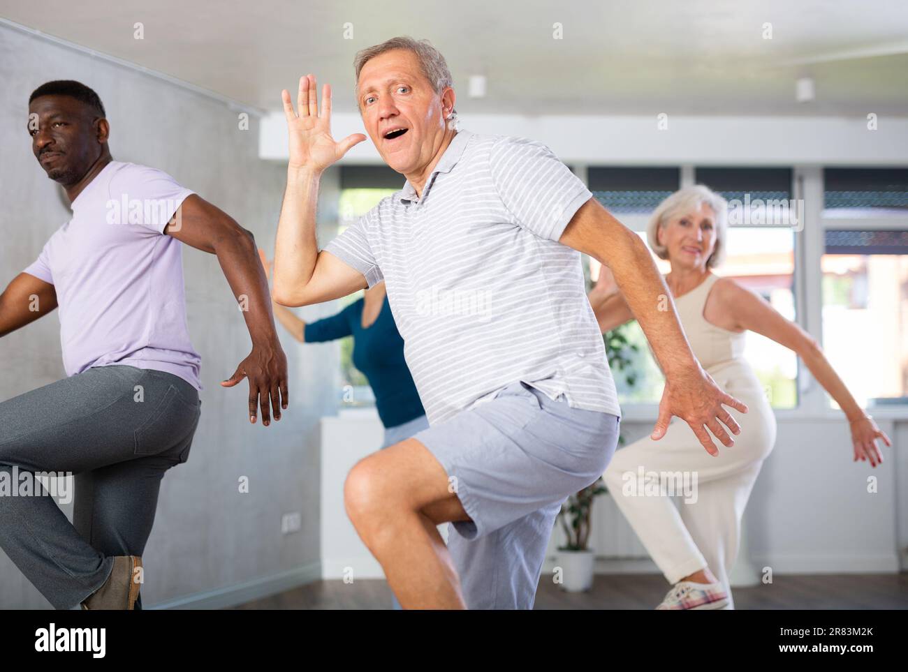 Positive senior man practicing vigorous dance during group class Stock ...