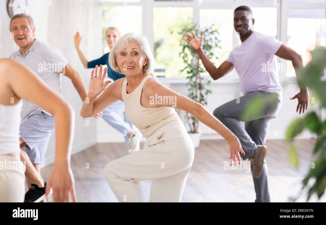 Elderly woman learning modern dynamic dances during group class Stock ...
