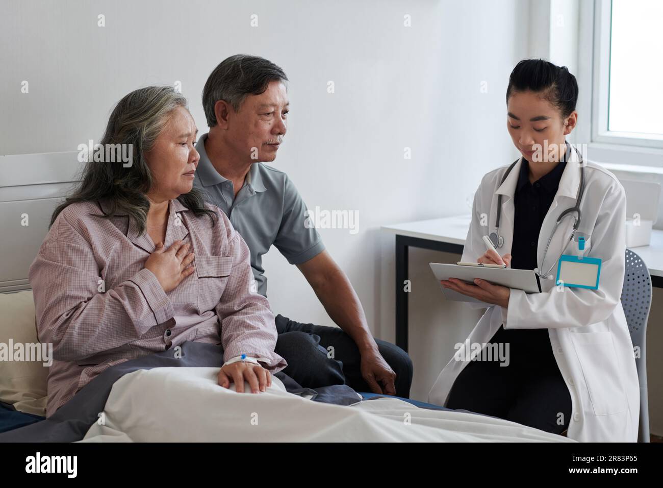 General practitioner taking notes when talking to sick senior woman and ...