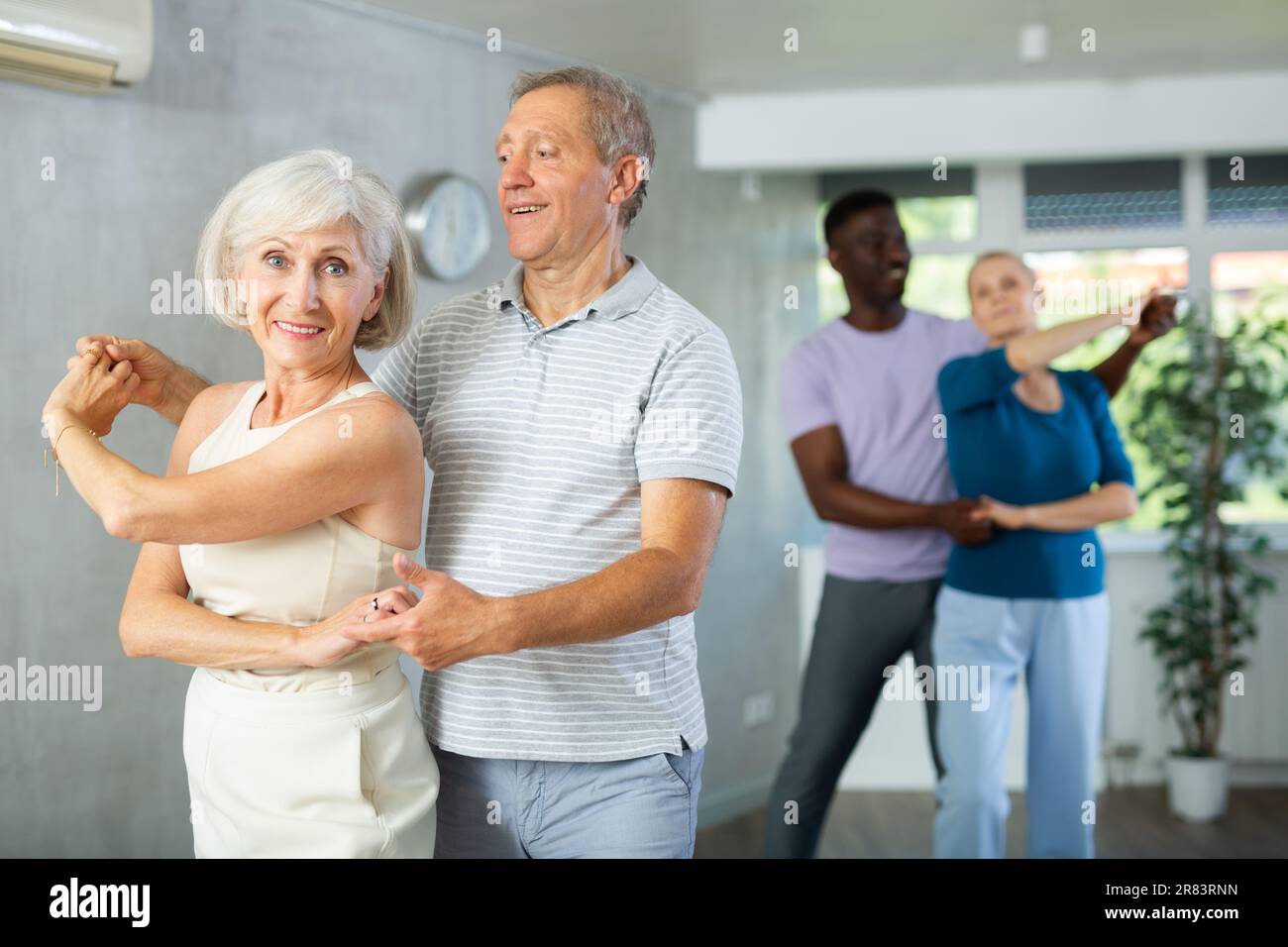 Elderly woman dancing merengue with male partner in latin dance class ...