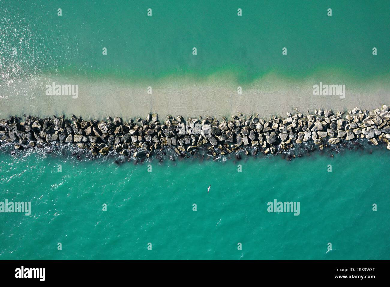 An aerial view of Waves hitting sandy rock barrier Stock Photo - Alamy