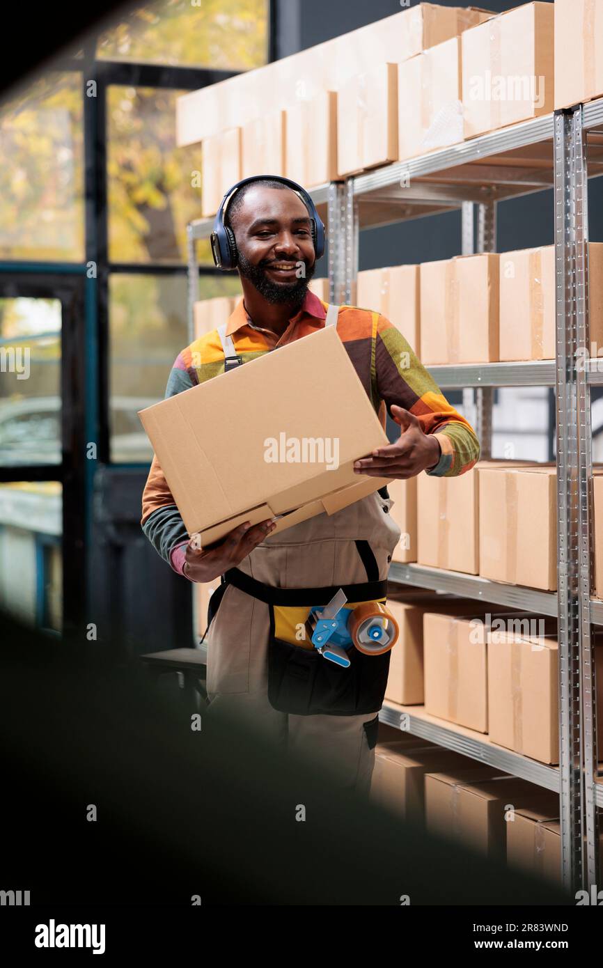 Storage room employee working at goods distribution, carrying cardboard ...