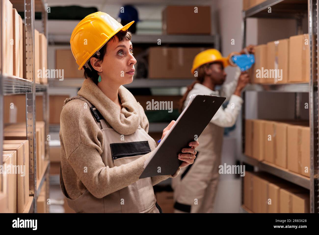 Operations warehouse manager taking notes in stockroom, wearing ...