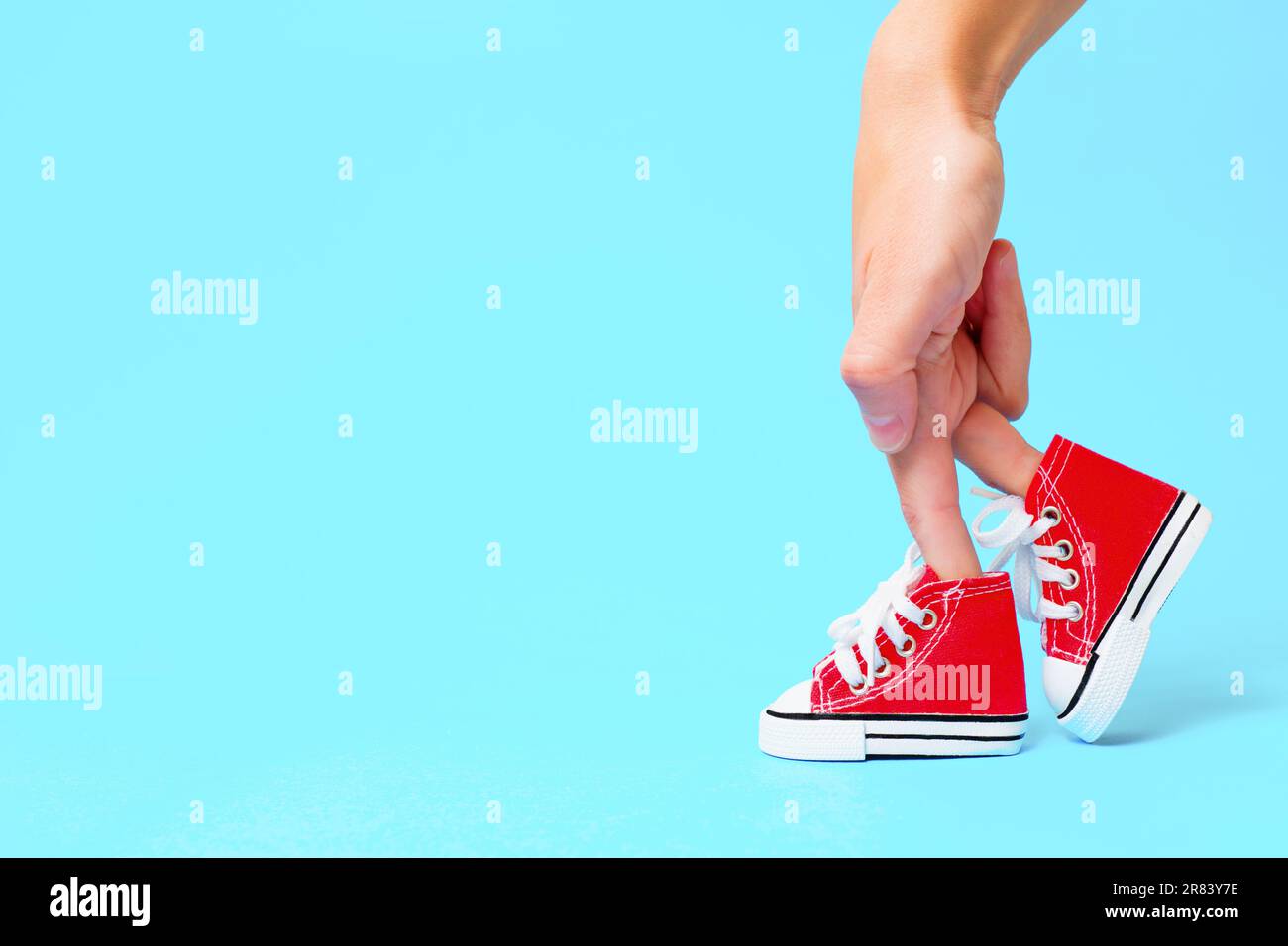 Female hand with fingers dressed in red canvas trainers and arranged to ...
